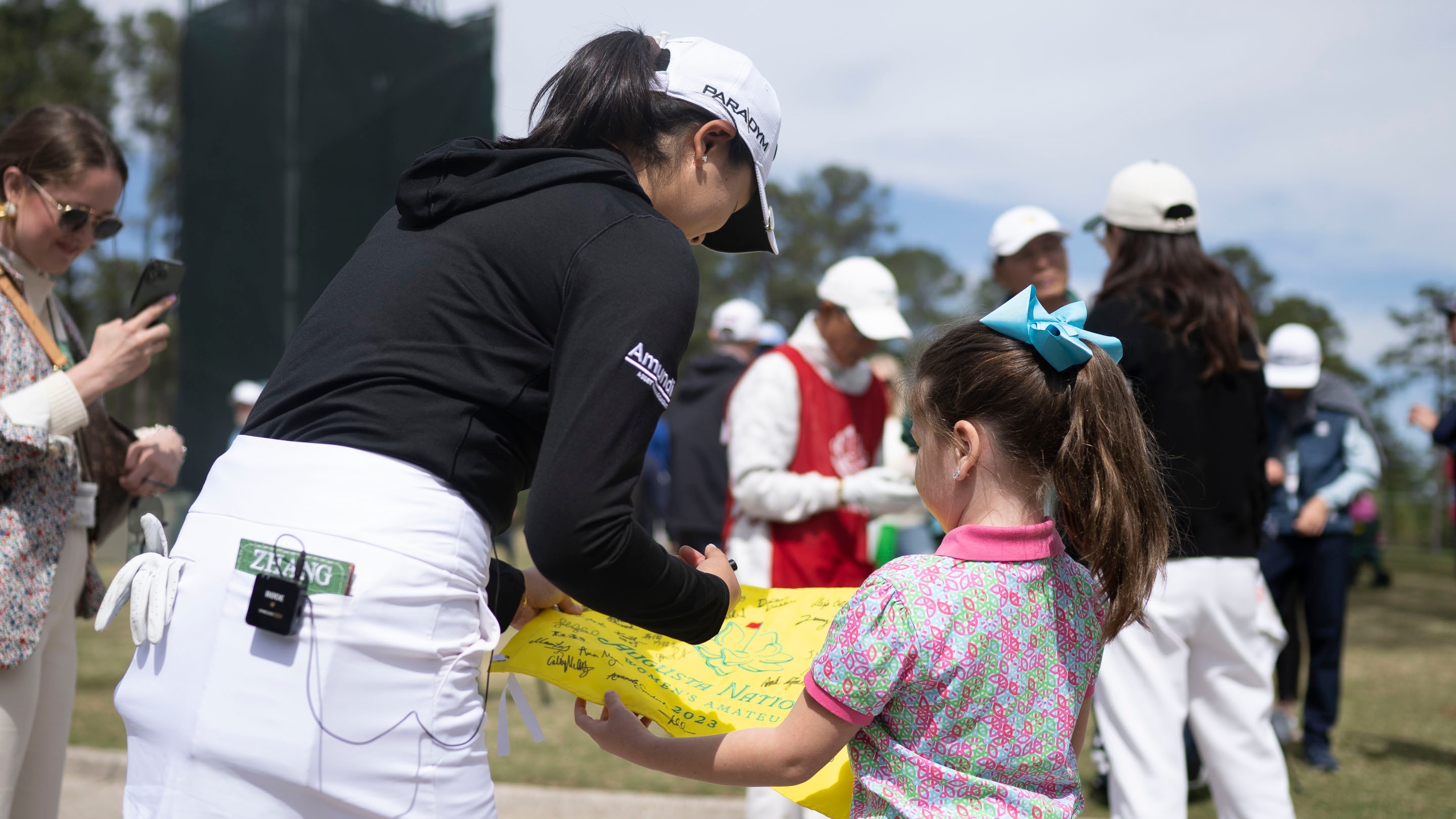 Rose Zhang signs an autograph for a young patron after the first round ...